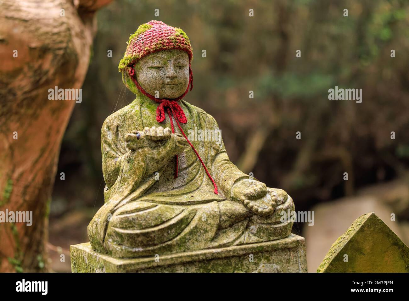 Stone statue of child sitting cross-legged wearing a knit cap at ...