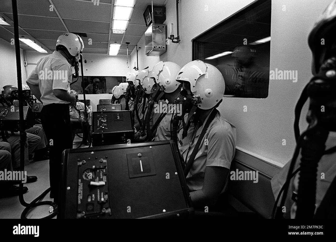 Midshipmen wearing flight helmets and oxygen masks prepare to undergo ...