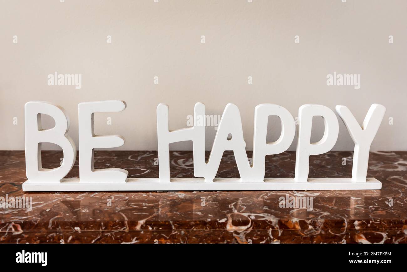 Be Happy sign, wooden cutout of text standing on a brown marble ...