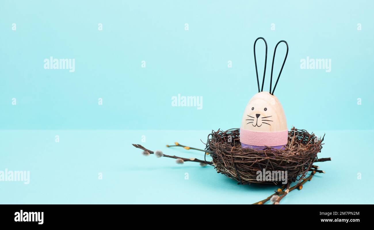 Easter bunny or rabbit sitting in a bird nest, willow branches, wooden ...