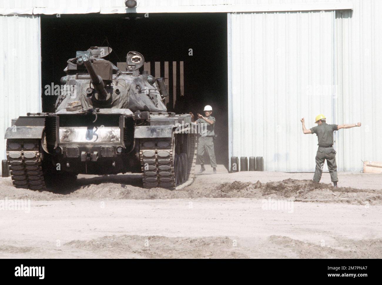 AN Army M-60 tank is being directed out of a warehouse during the ...