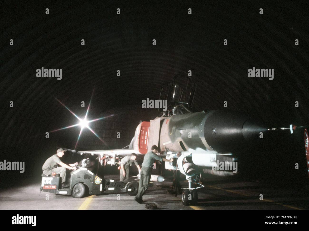 Weapons specialists load a missile on an F-4E Phantom II aircraft with ...