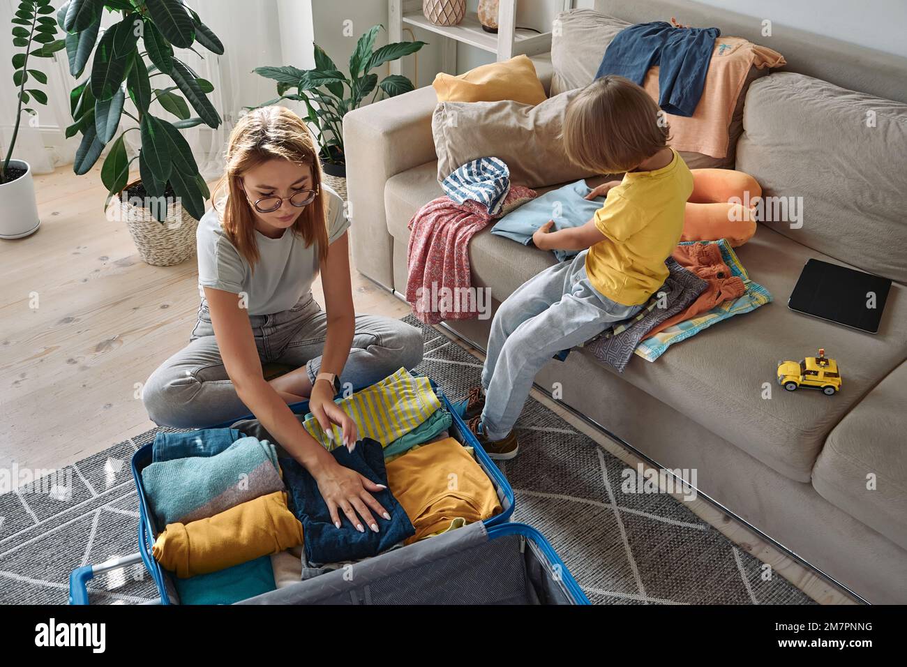 Family mother and child packing a suitcase together going on a trip or ...