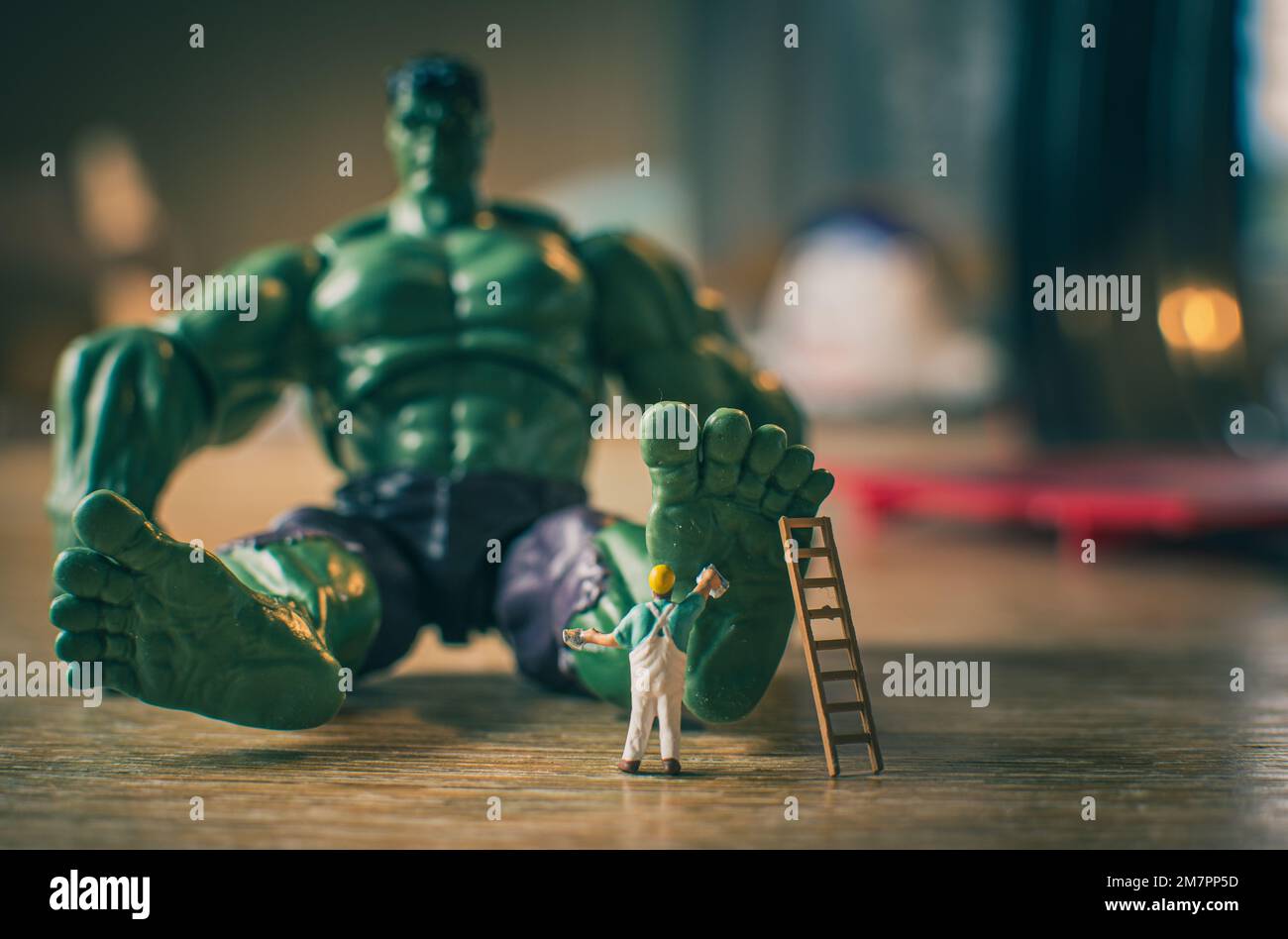 A closeup of a miniature person cleaning up a toy Hulk feet Stock Photo ...