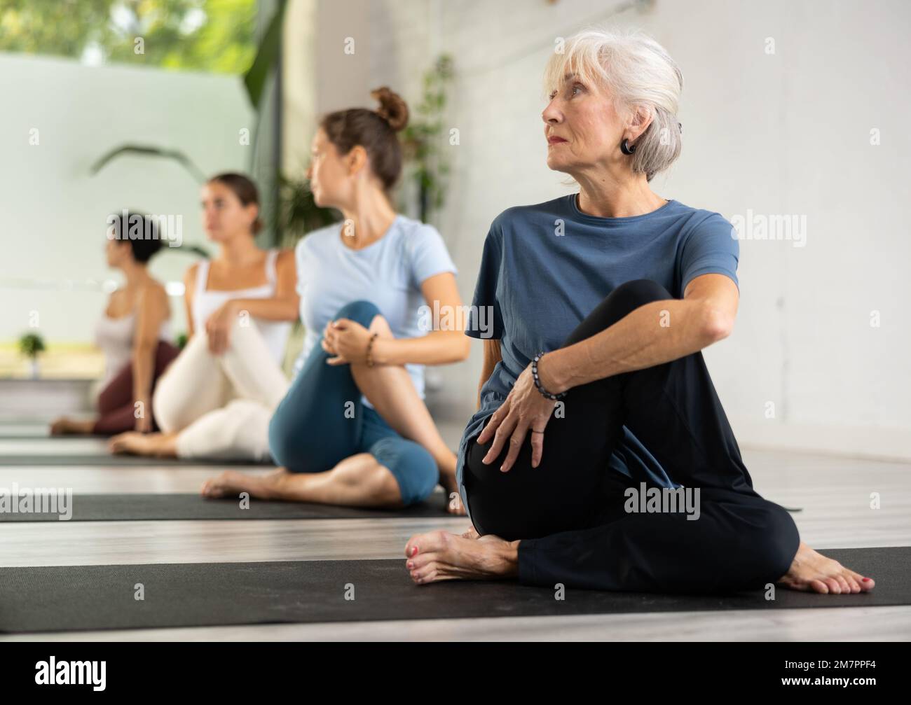 Group of sporty people practicing various yoga positions during ...