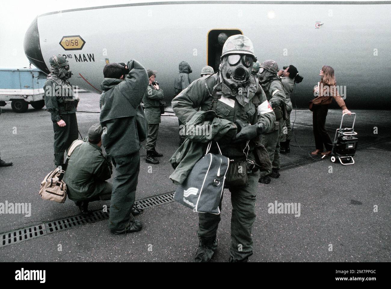U.S. troops, in chemical warfare gear, debark a C-141 Starlifter ...