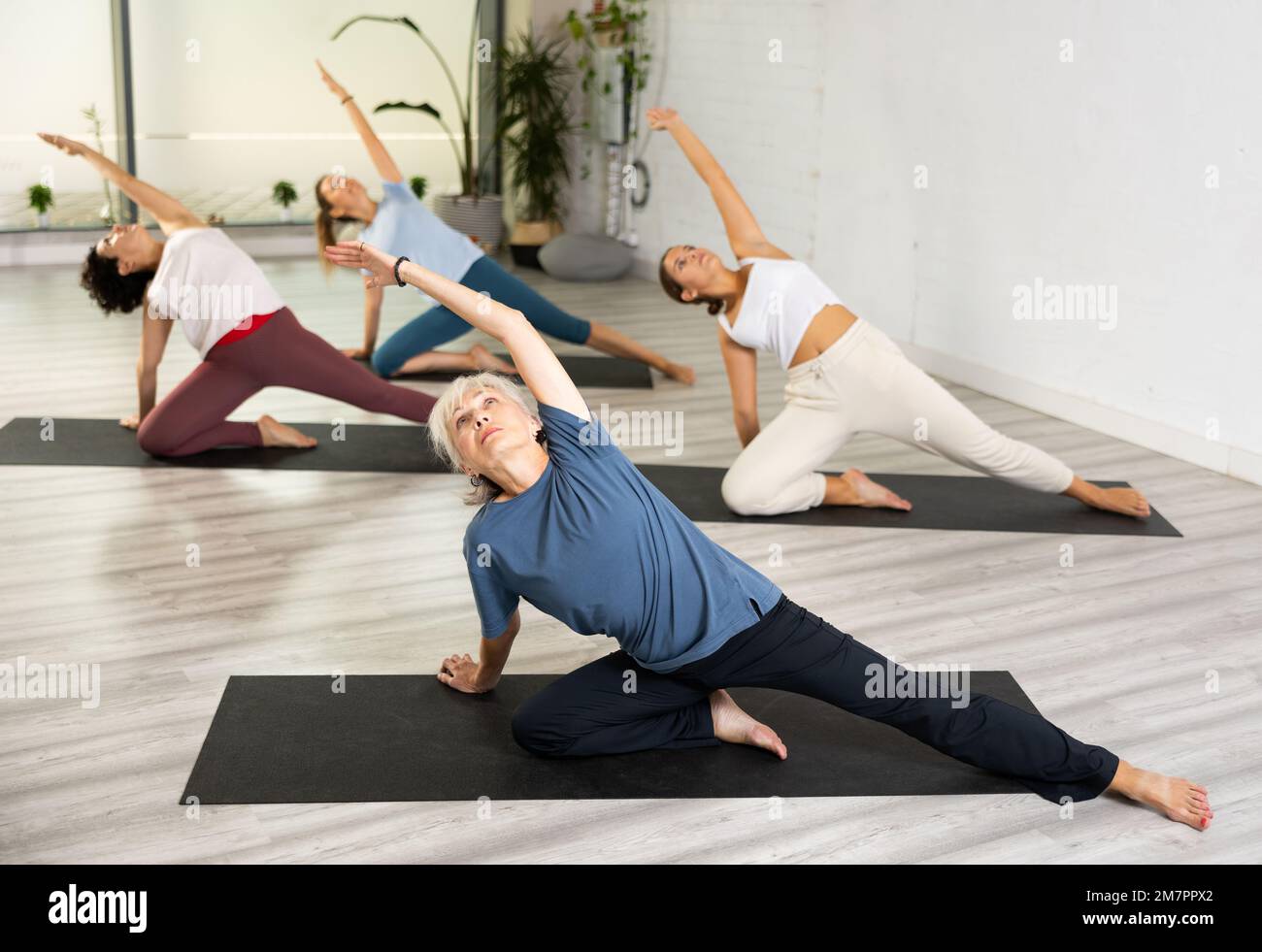Group of young active different ages women doing stretching exercises ...