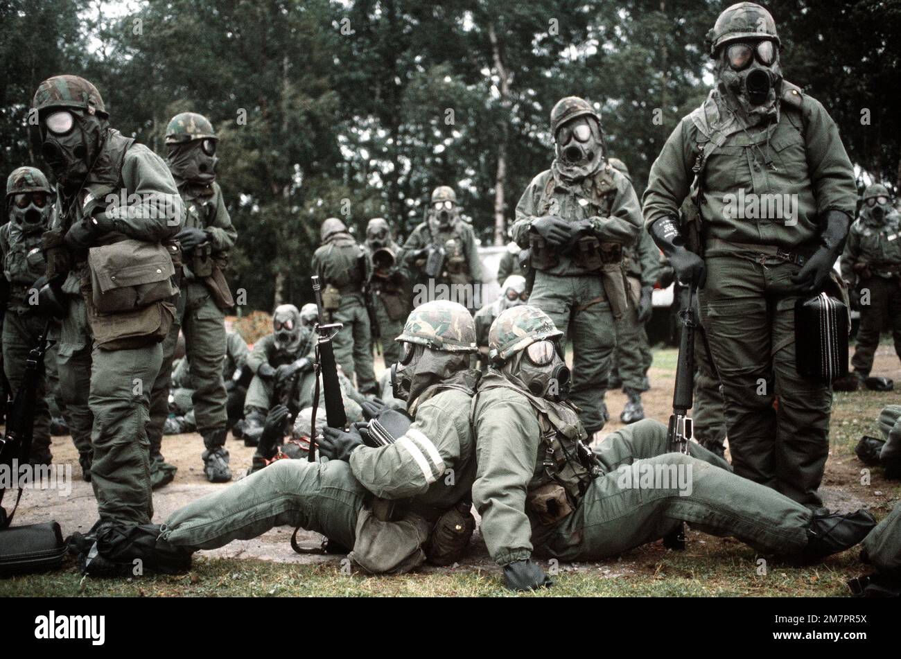 Troops wearing their chemical warfare gear wait for their flight ...