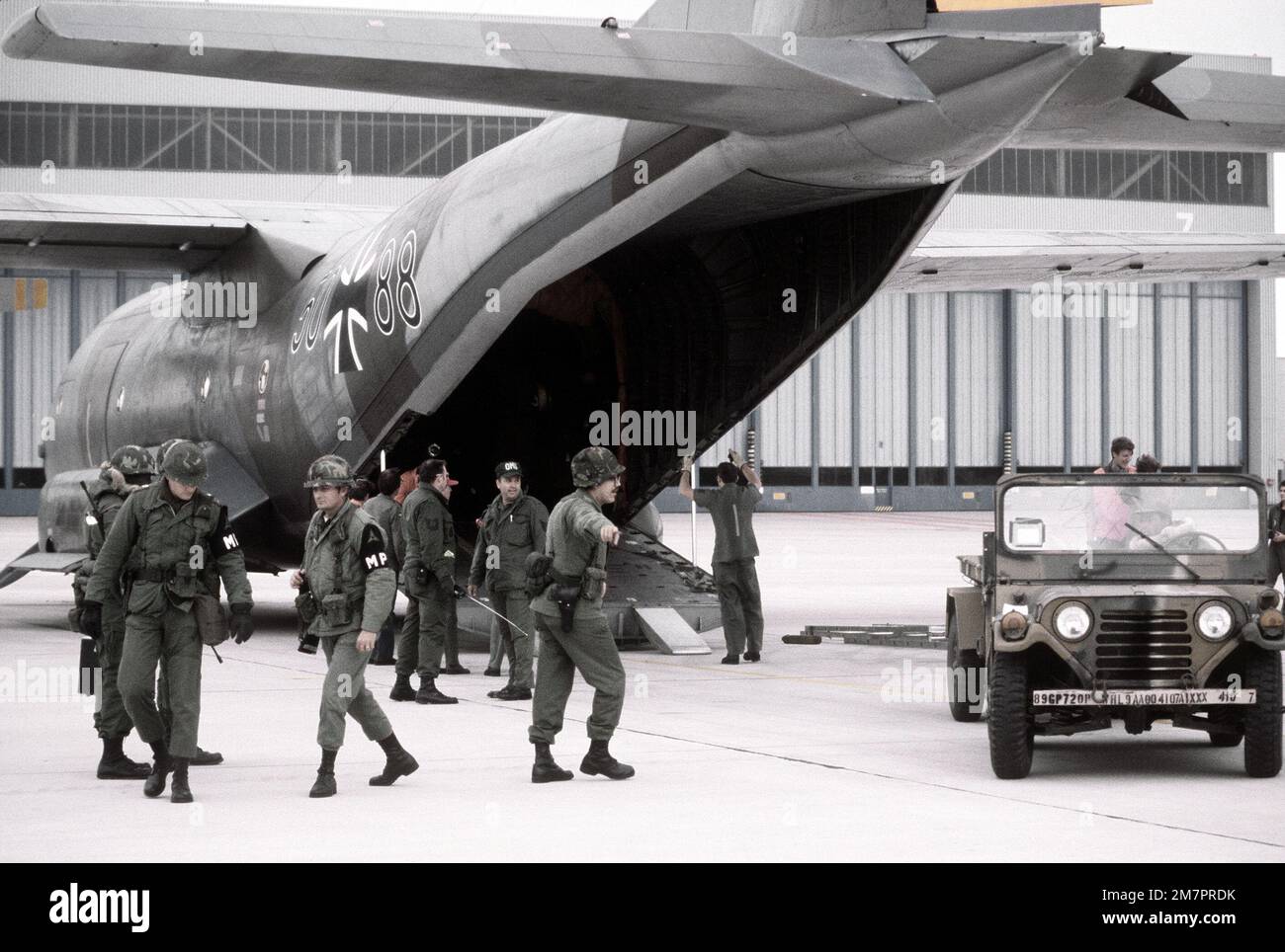 A military policeman directs a jeep to a parking area after it is ...