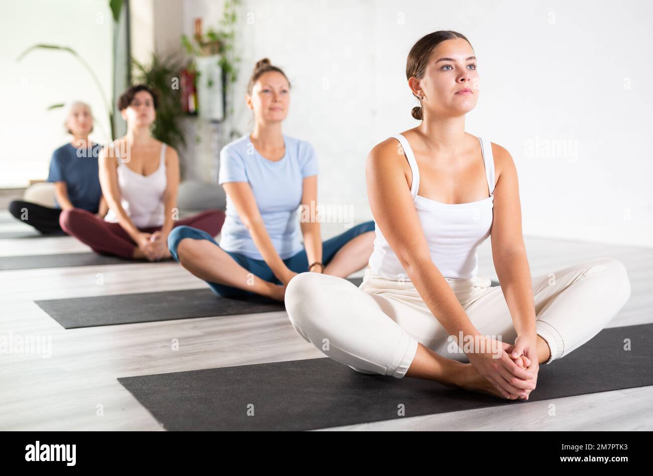 Concentrated young woman performing Butterfly Pose Baddha Konasana ...