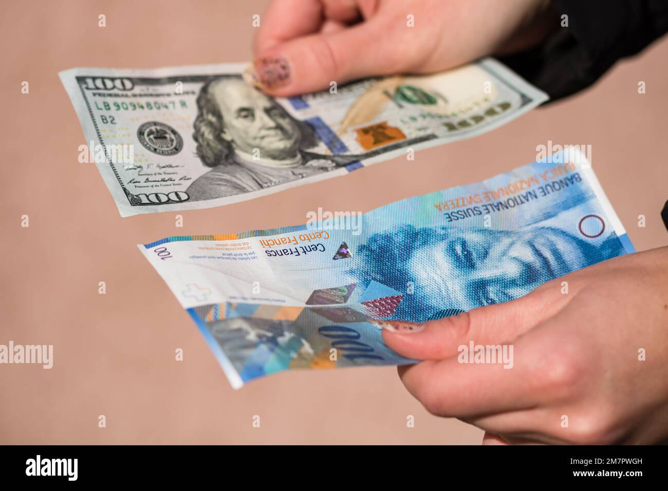 Hand holding money isolated on banknotes background. USD and CHF ...
