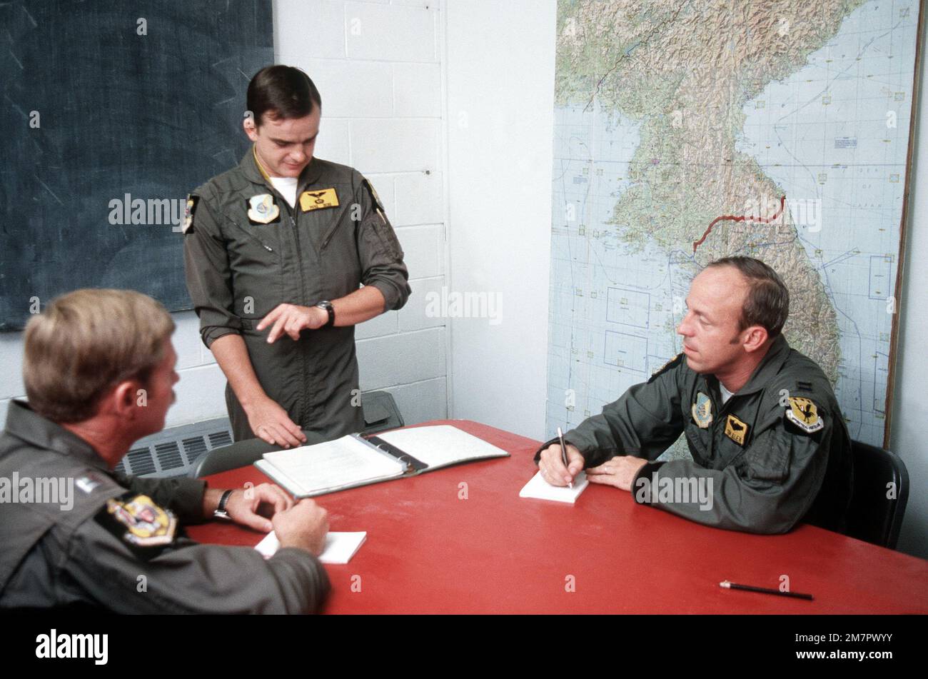 Three members of the 18th Fighter Wing, Tactical Air Command, confer ...