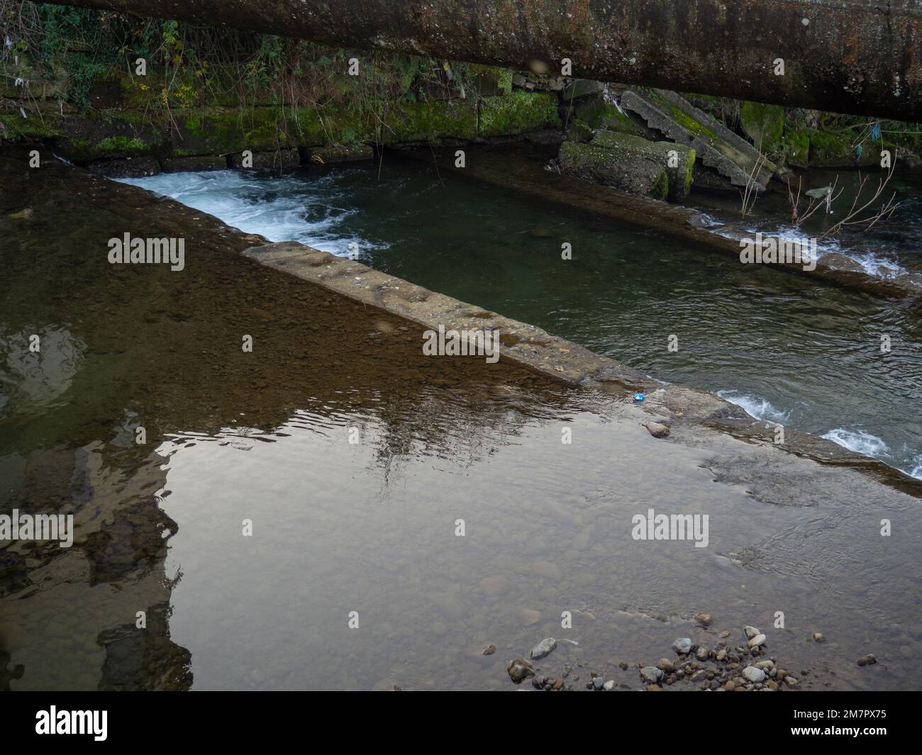 Heating main over the stream. Industry and nature. Fast river in the ...