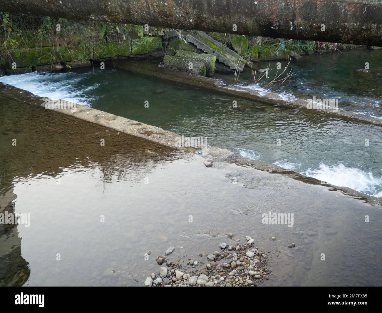 Heating main over the stream. Industry and nature. Fast river in the ...