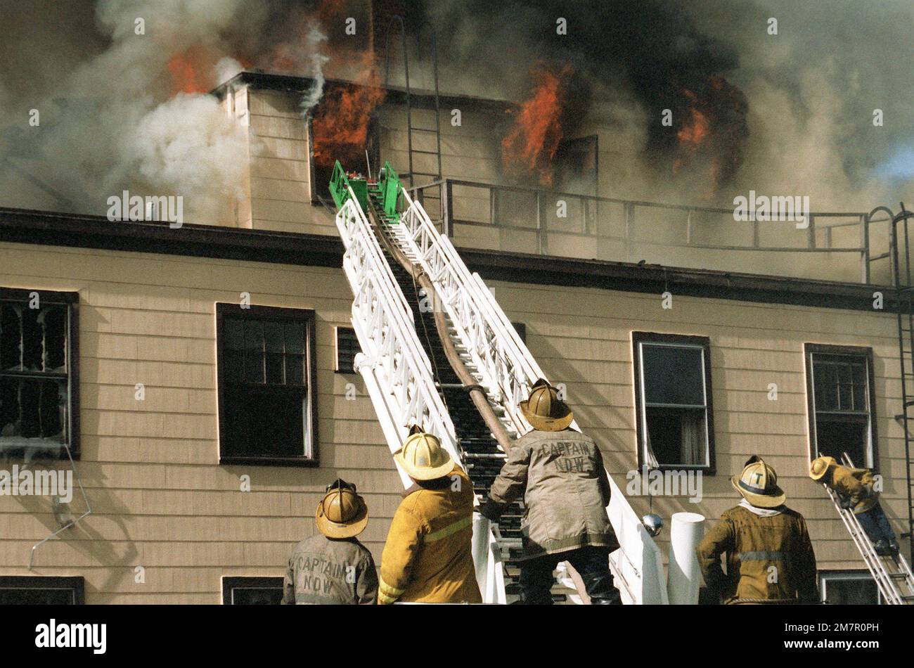 Firemen raise a fire-engine tower ladder toward one of the windows of ...