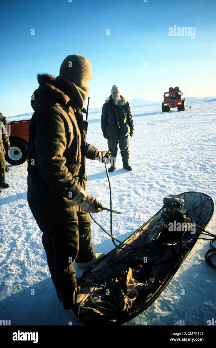 U.S. Navy ground support personnel ready a sled-mounted air pump during ...