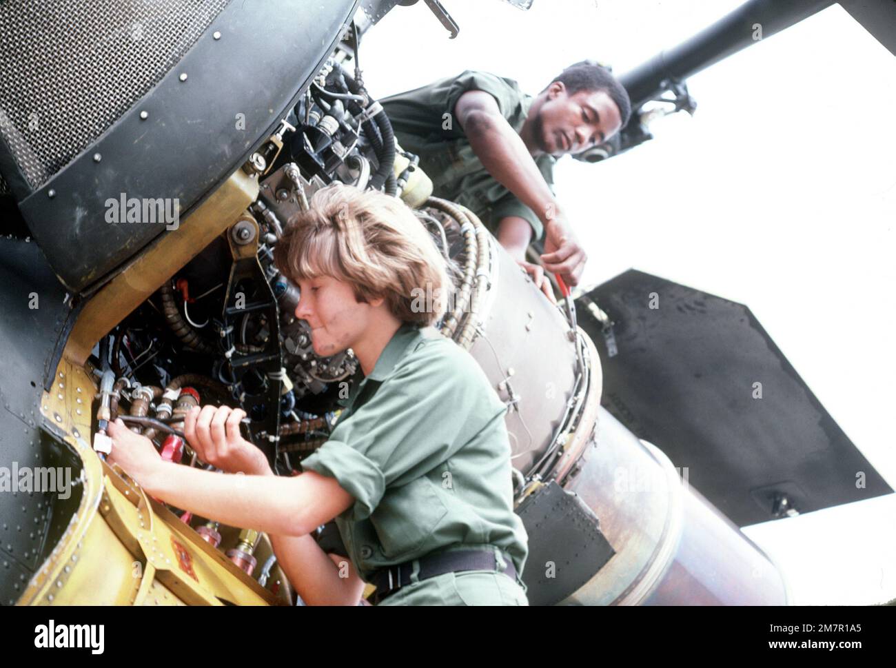 A female U.S. Army mechanic services a CH-47 Chinook helicopter engine ...