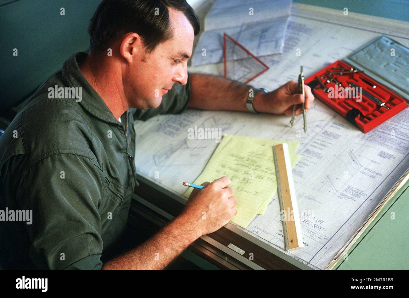 A U.S. Army draftsman uses drafting equipment to check a blueprint ...