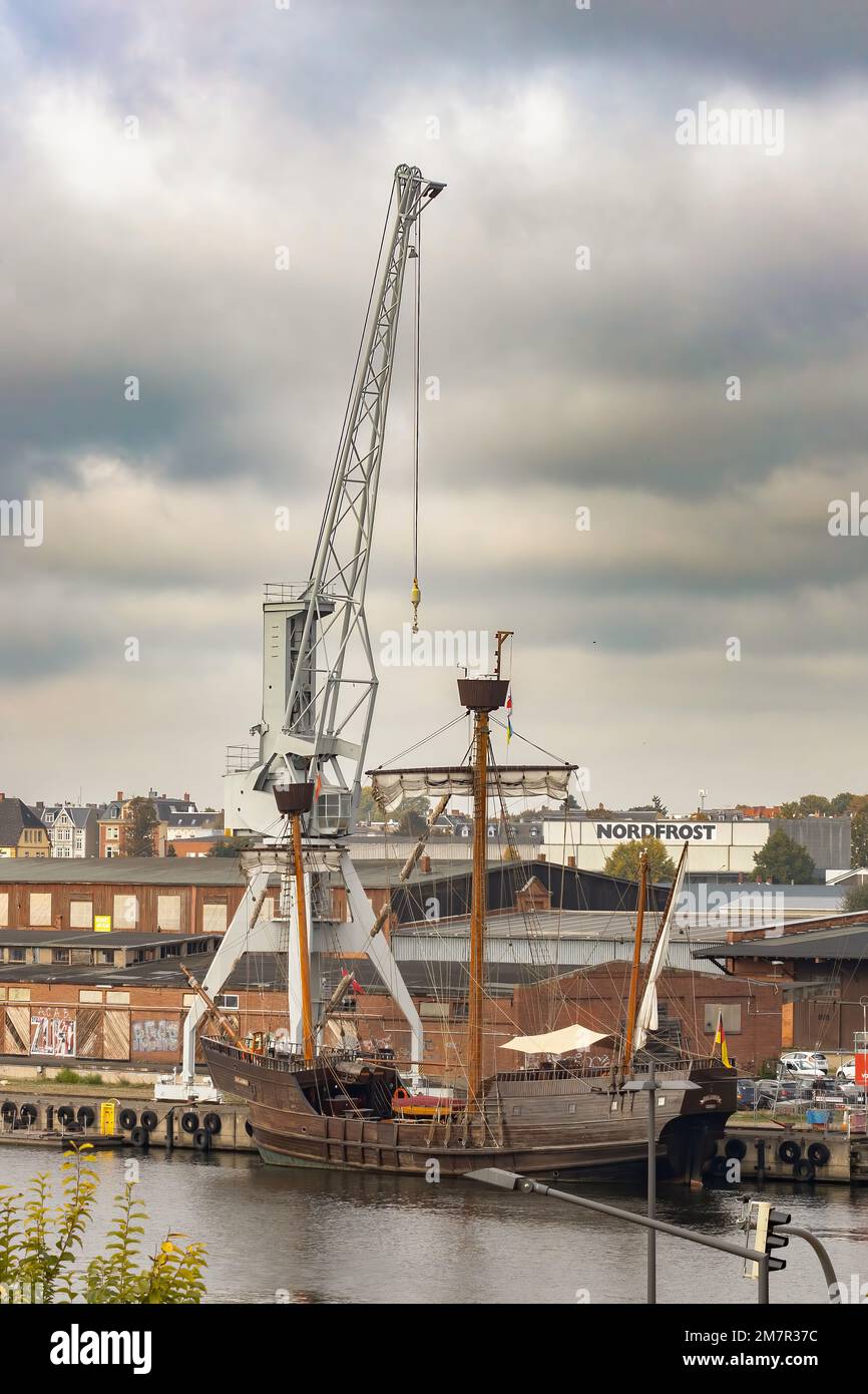 part of the port in Lübeck with a crane and a replica of anhanseatic ...