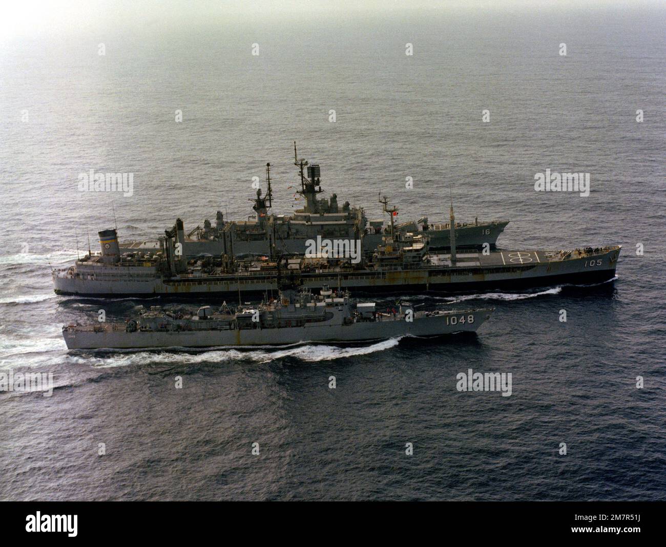 An aerial starboard beam view of, front to back: the frigate USS SAMPLE (FF 1048), the oiler USS ...