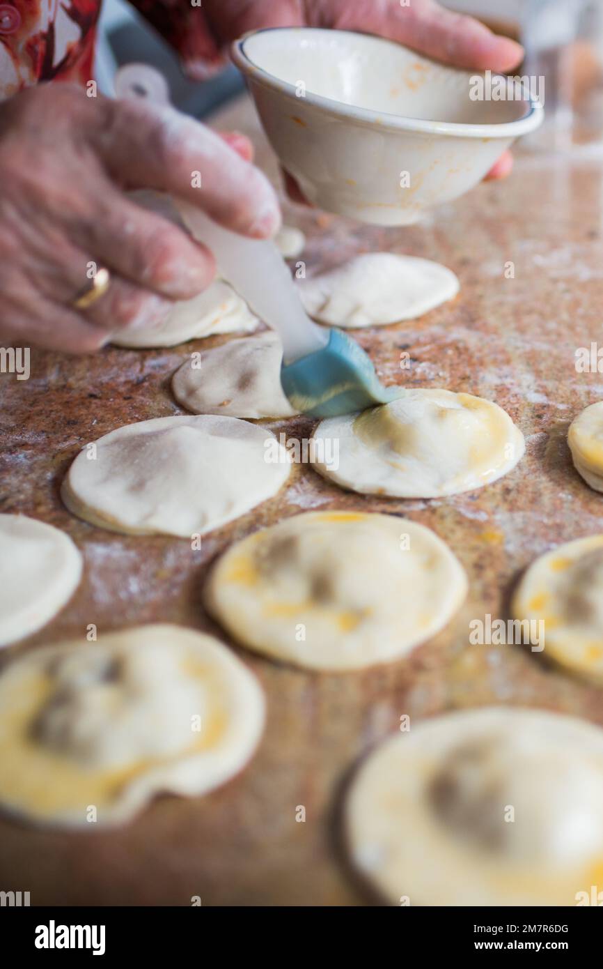 Close up of human hand preparing puff pastry damplings. Coating with ...