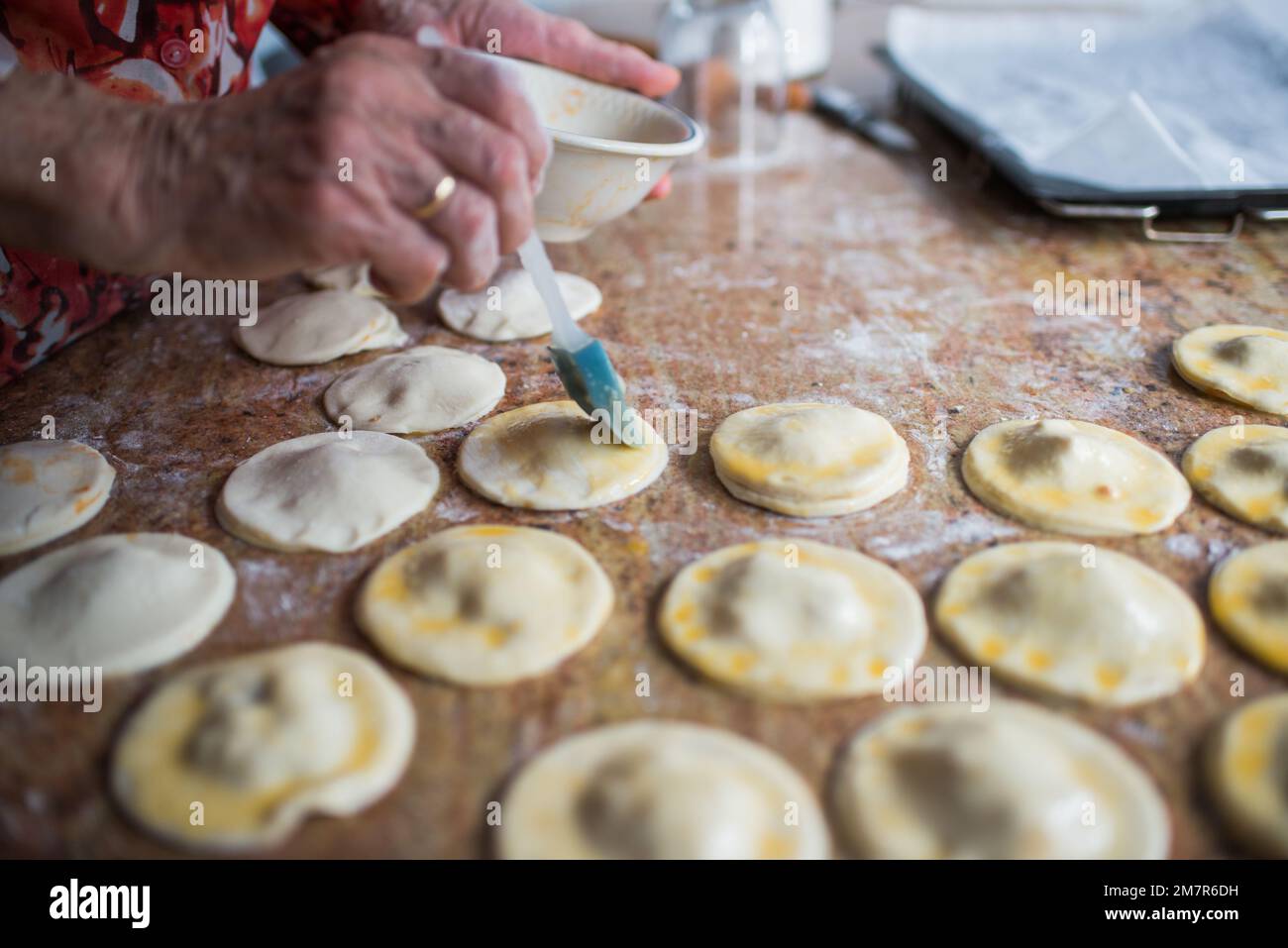 Close up of human hand preparing puff pastry damplings. Coating with ...