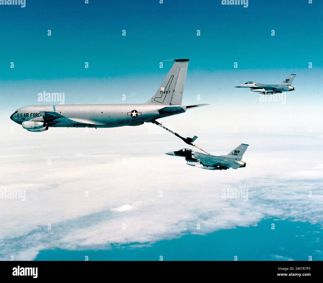 A left side view of a KC-135 Stratotanker aircraft refueling an F-16A ...