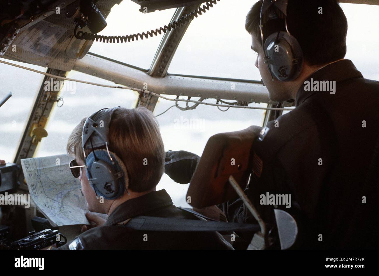 A C-130 Hercules aircraft copilot and navigator use a map to check ...