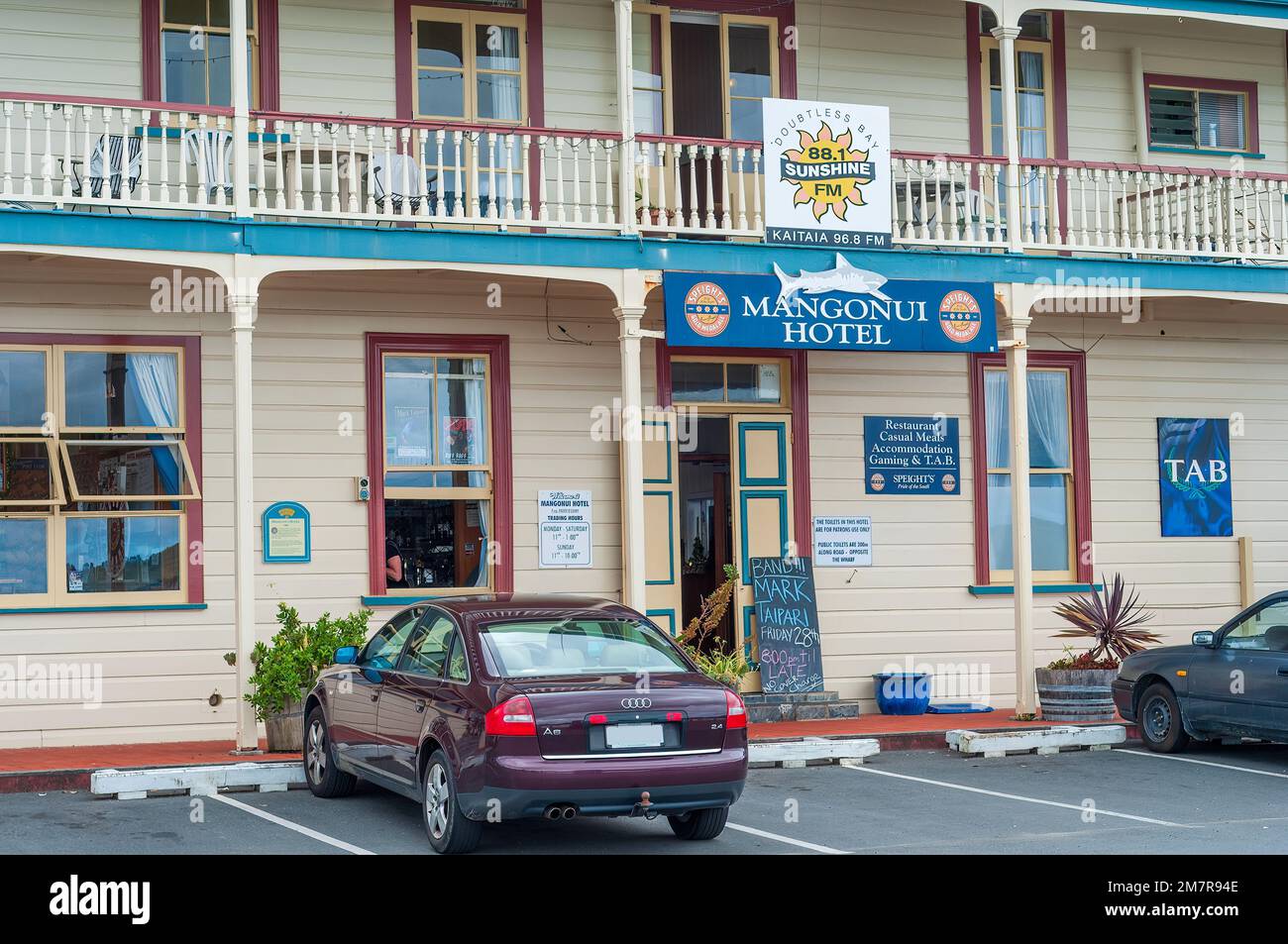A closeup of cars parked on the waterfront road in front of a hotel in ...