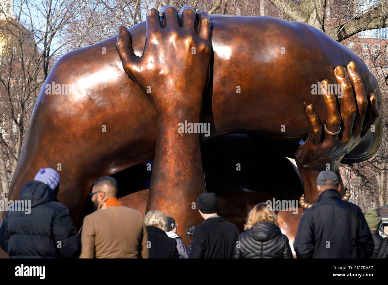 People stand near the 20-foot-high bronze sculpture "The Embrace," a ...