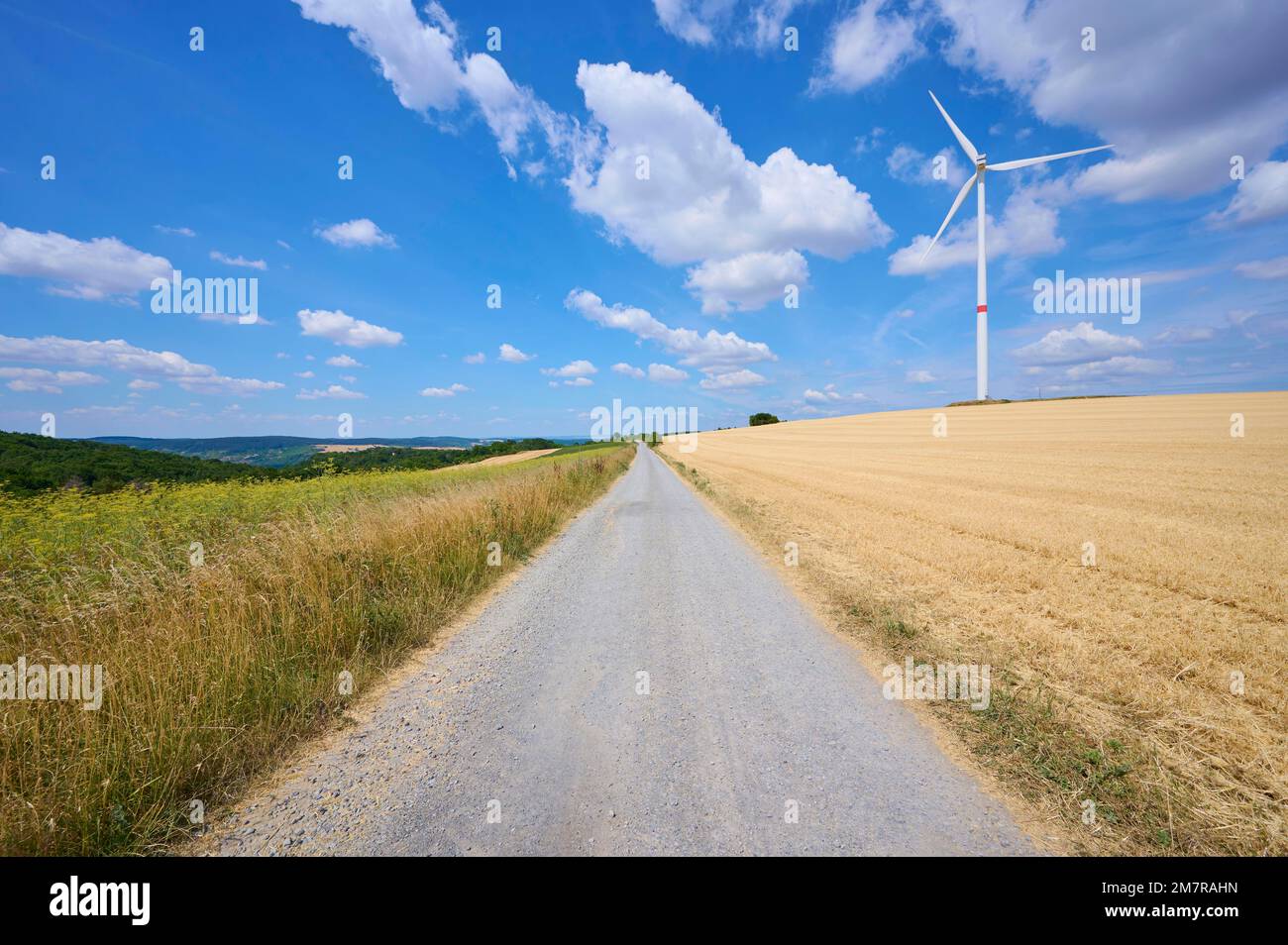 Dirt road in landscape with wind turbine in summer, Wuerzburg ...