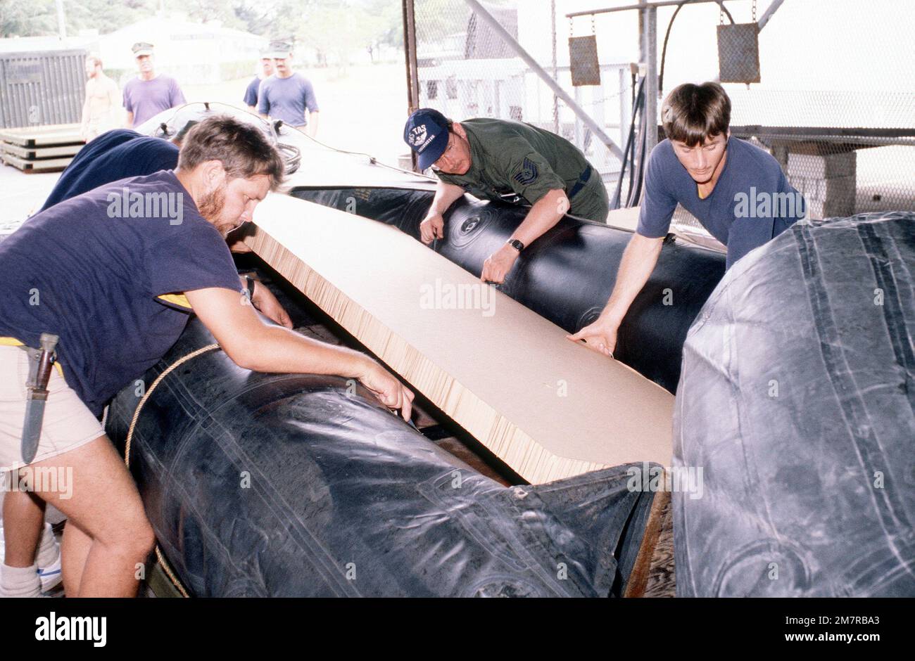 Military personnel install honeycomb sub-flooring in a rubber raft as ...