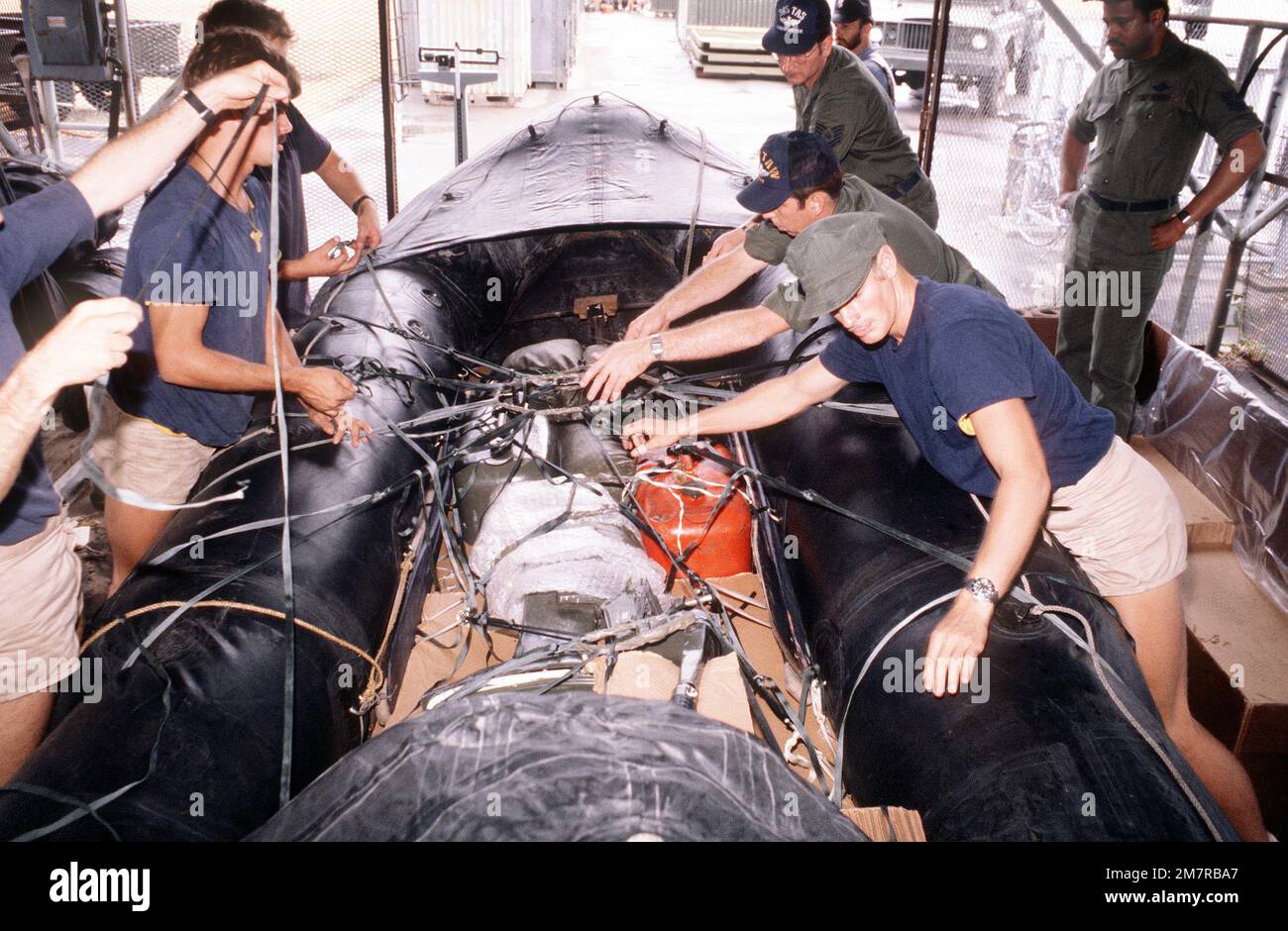 Military personnel equip a rubber raft prior to loading it aboard a C ...