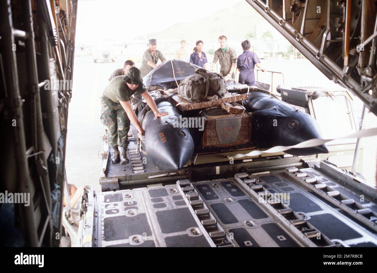 Military personnel load a fully outfitted rubber raft aboard a C-130 ...