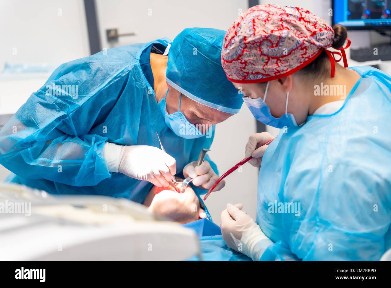Doctors in blue gowns performing a complicated operation on a patient ...