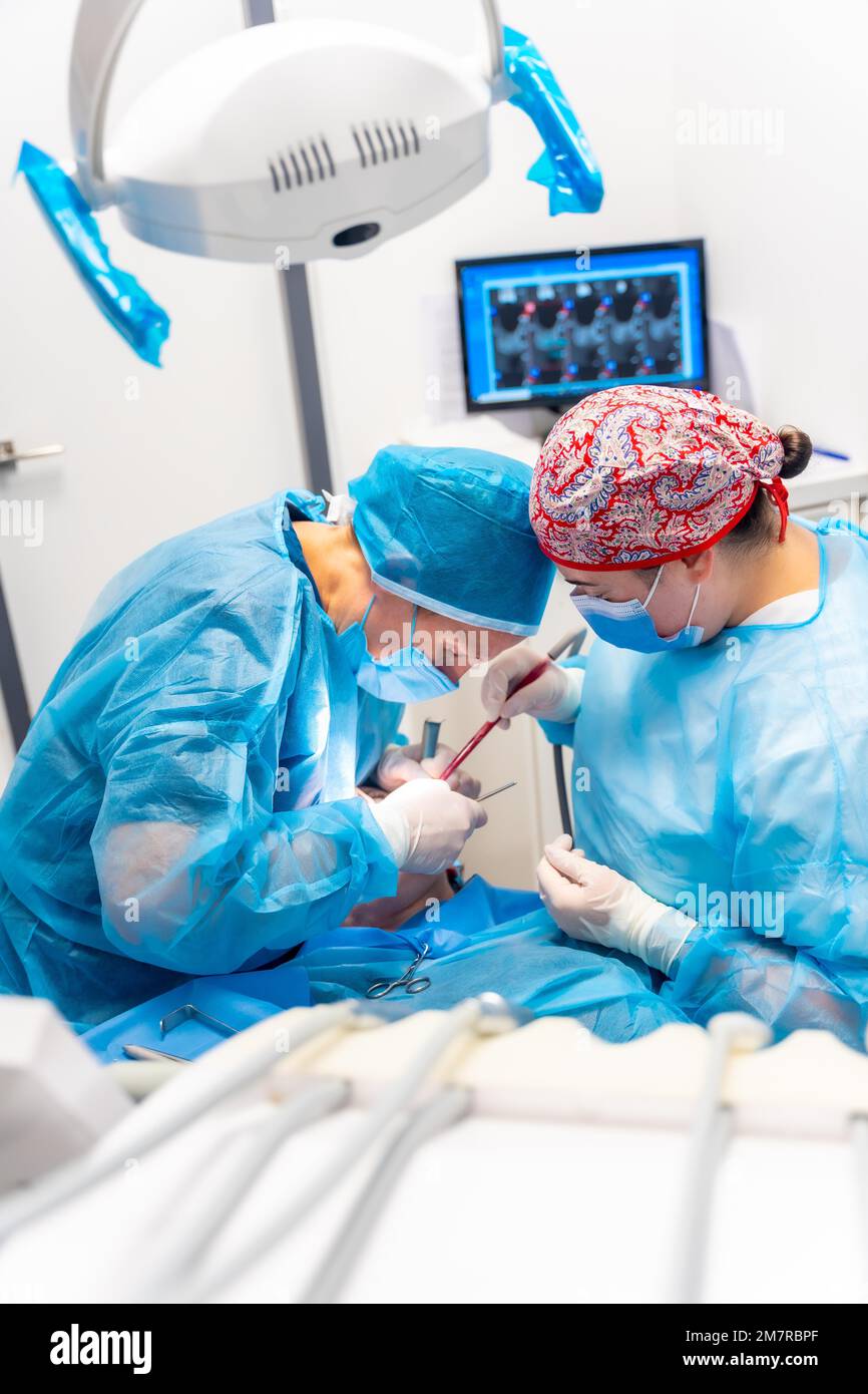 Doctors in blue gowns performing a complicated operation on a patient ...