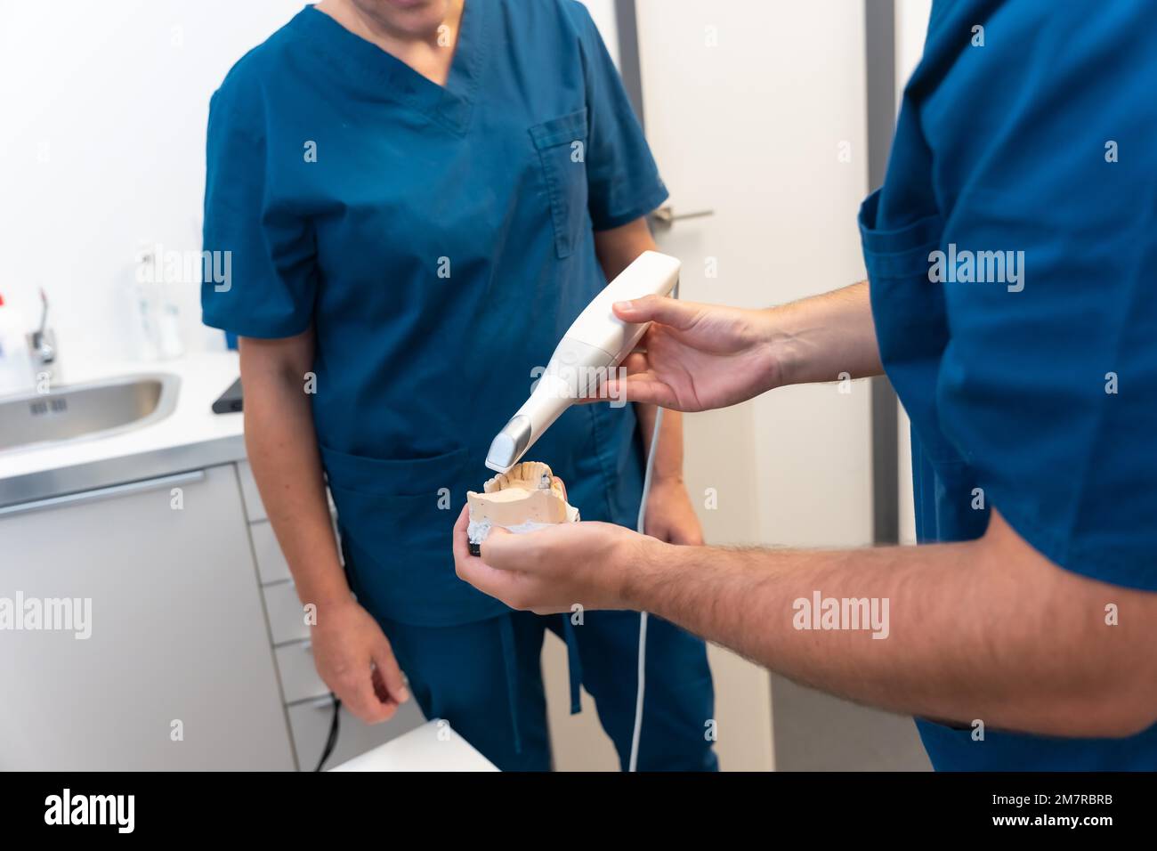A doctor in the dental clinic explaining to a female doctor how to scan ...