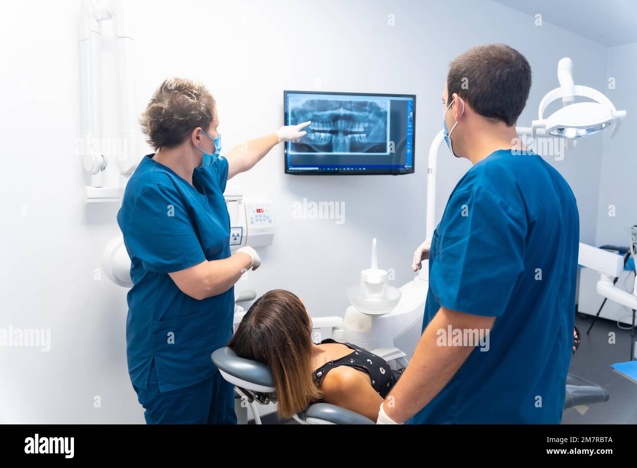Dental clinic, sitting patient talking to dentists about her teeth on x ...