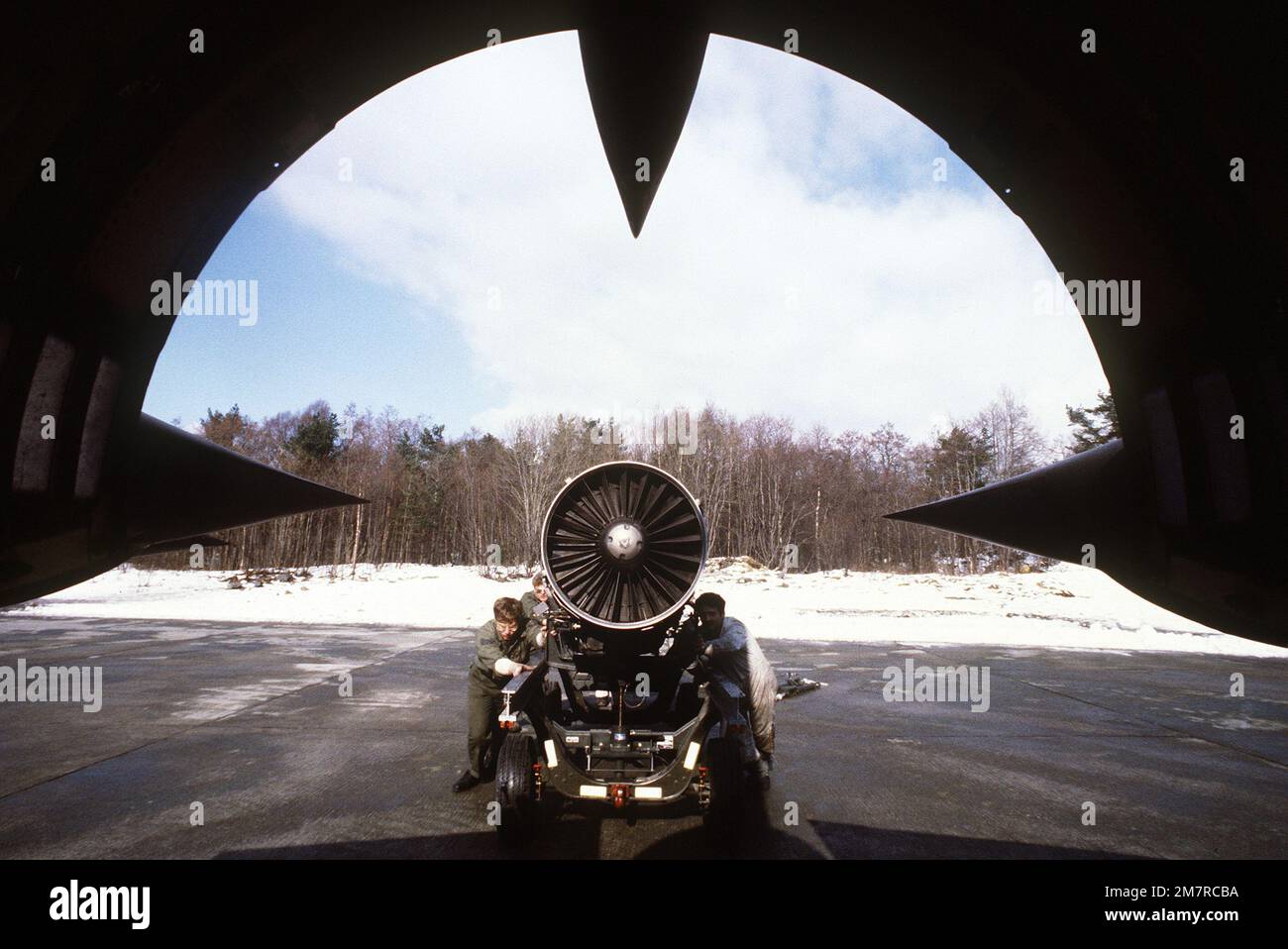 AN engine is moved toward an F-16 Fighting Falcon aircraft for an ...