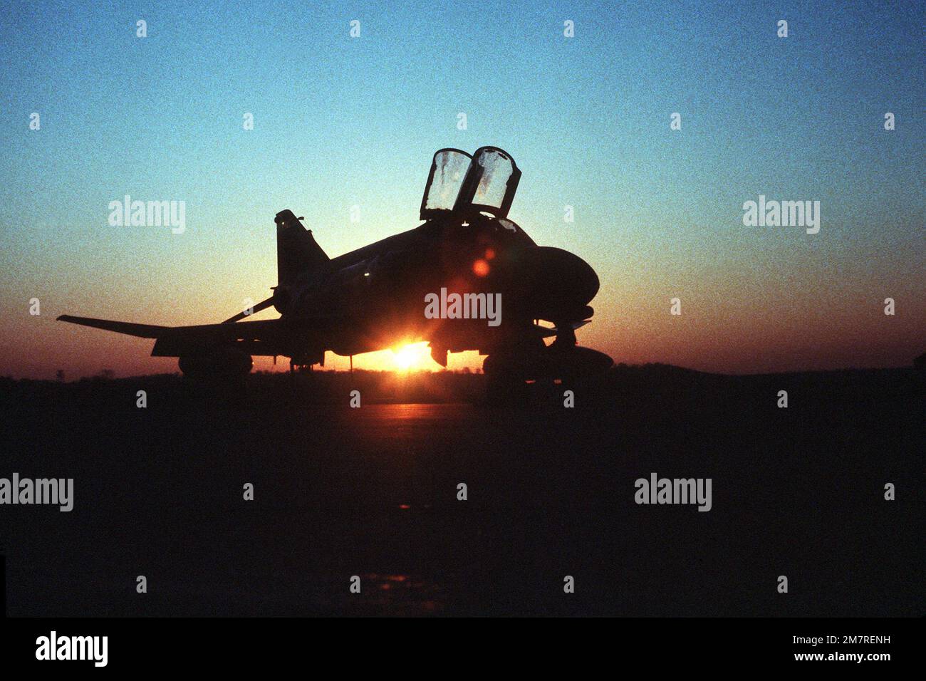 A left side view of an F-4C Phantom II aircraft, with the sunrise in ...
