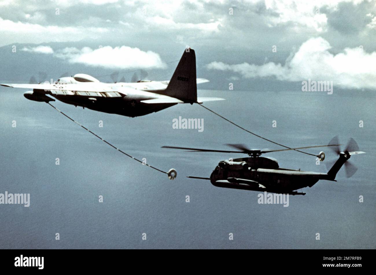 A left rear view of an HC-130P Hercules aircraft refueling a CH-53C ...