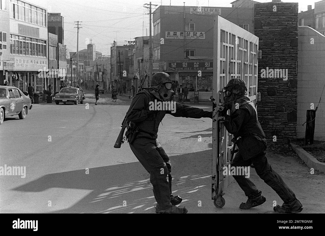 Security policemen, wearing chemical warfare gear, close the base gate ...