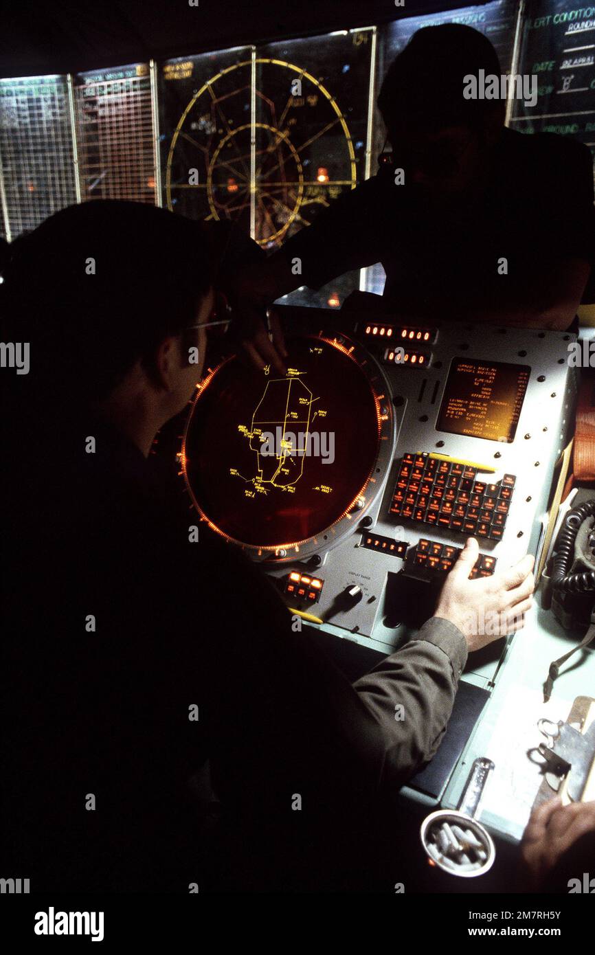 An airman explains objects depicted on a radar scope screen to a radar ...