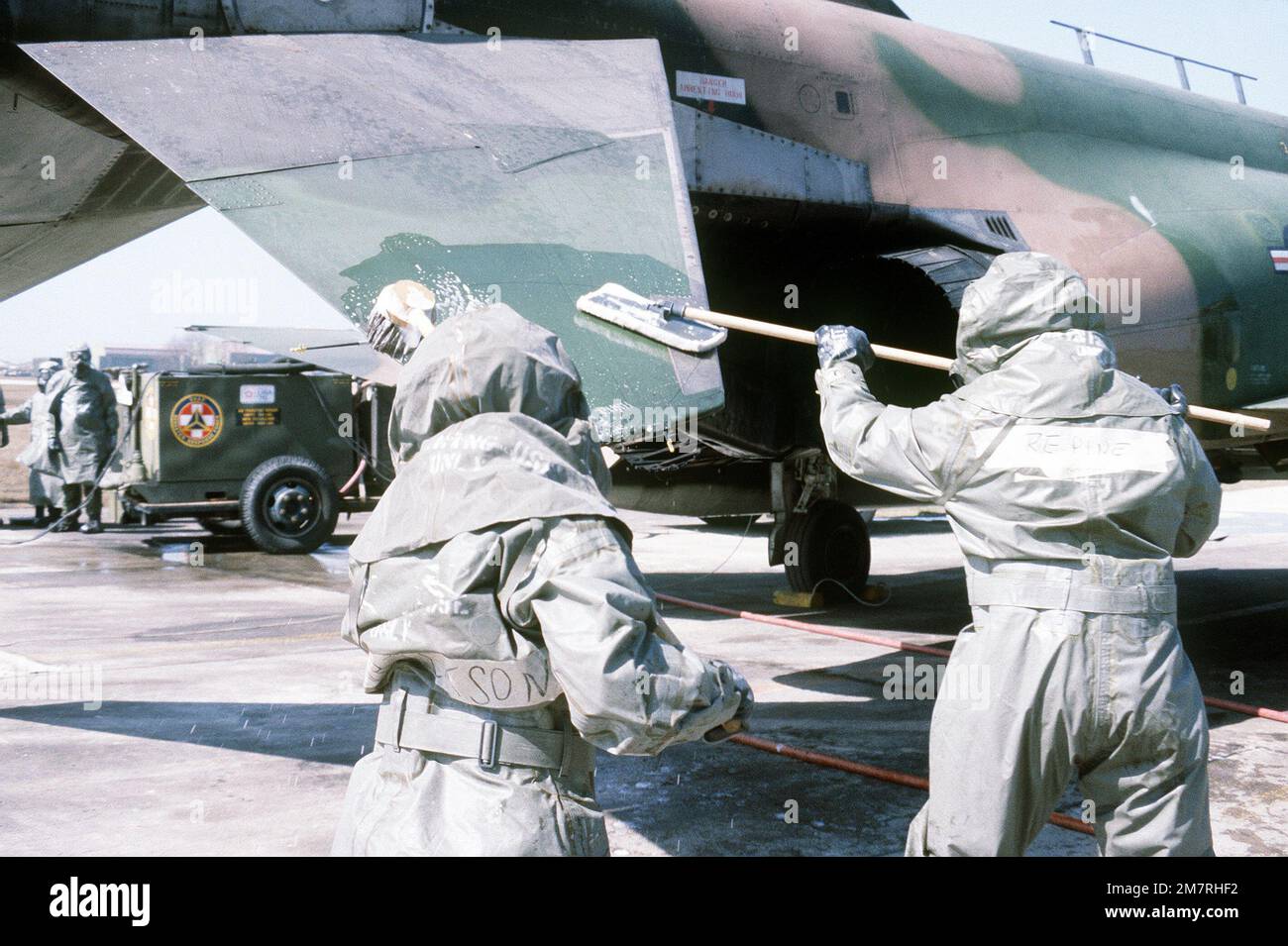 Airmen, clad in chemical warfare gear, perform F-4 Phantom II aircraft ...