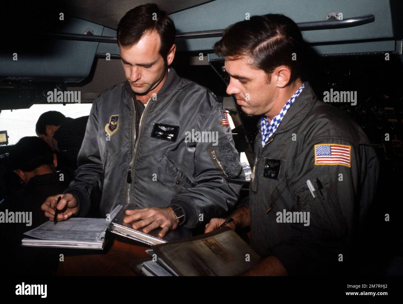 CPT Dano Kinzie and TSGT Richard Brooks use a flight log to check the ...