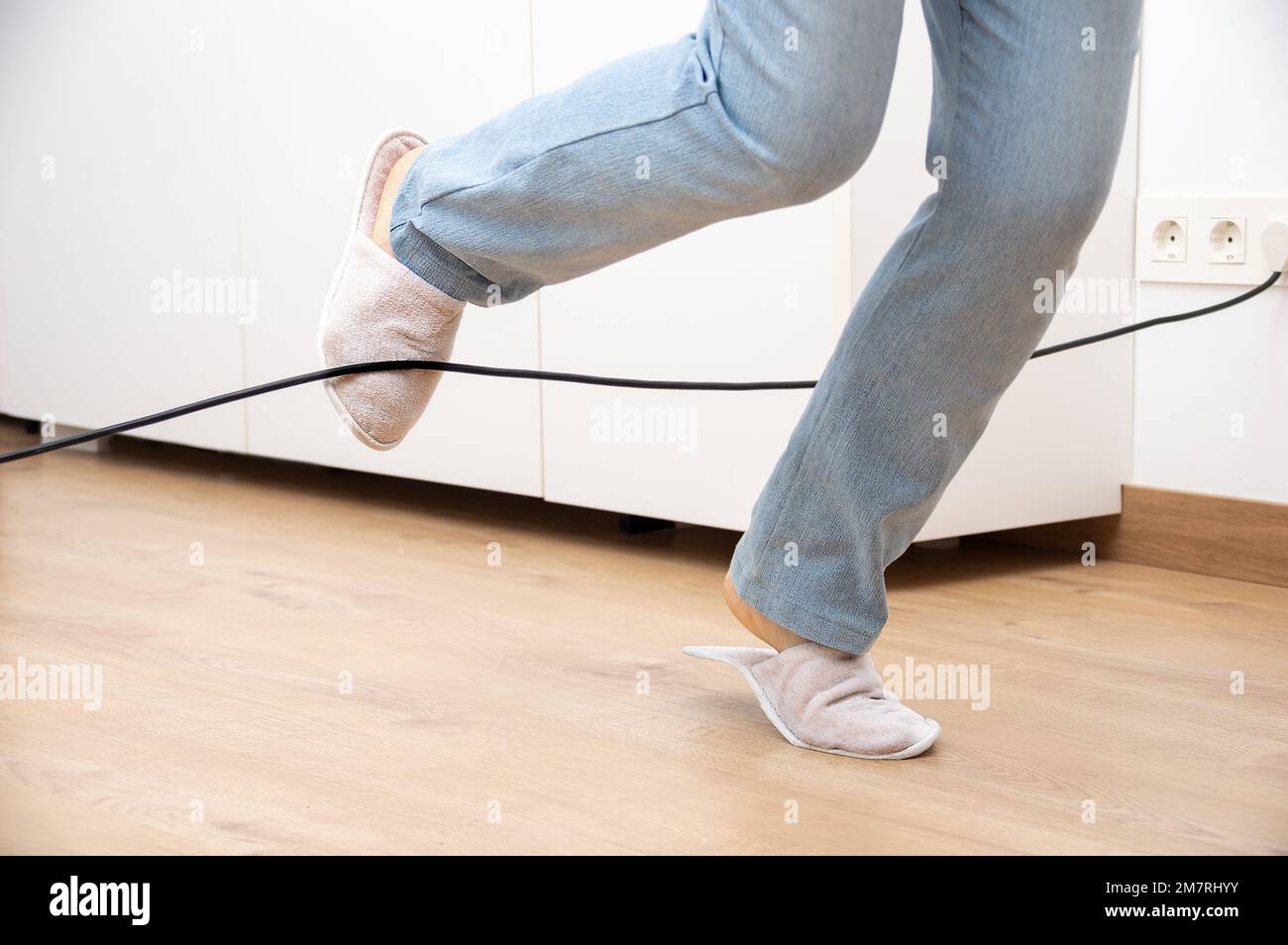 Close up of a woman legs stumbling with an electrical cord at home ...