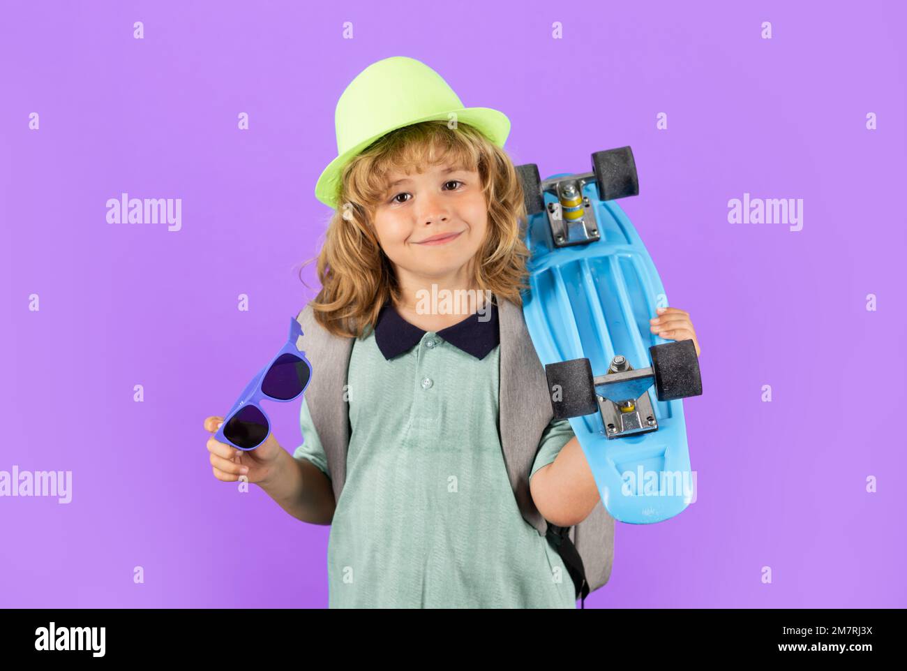 Child boy holding longboard on violet isolated background. Kid with ...