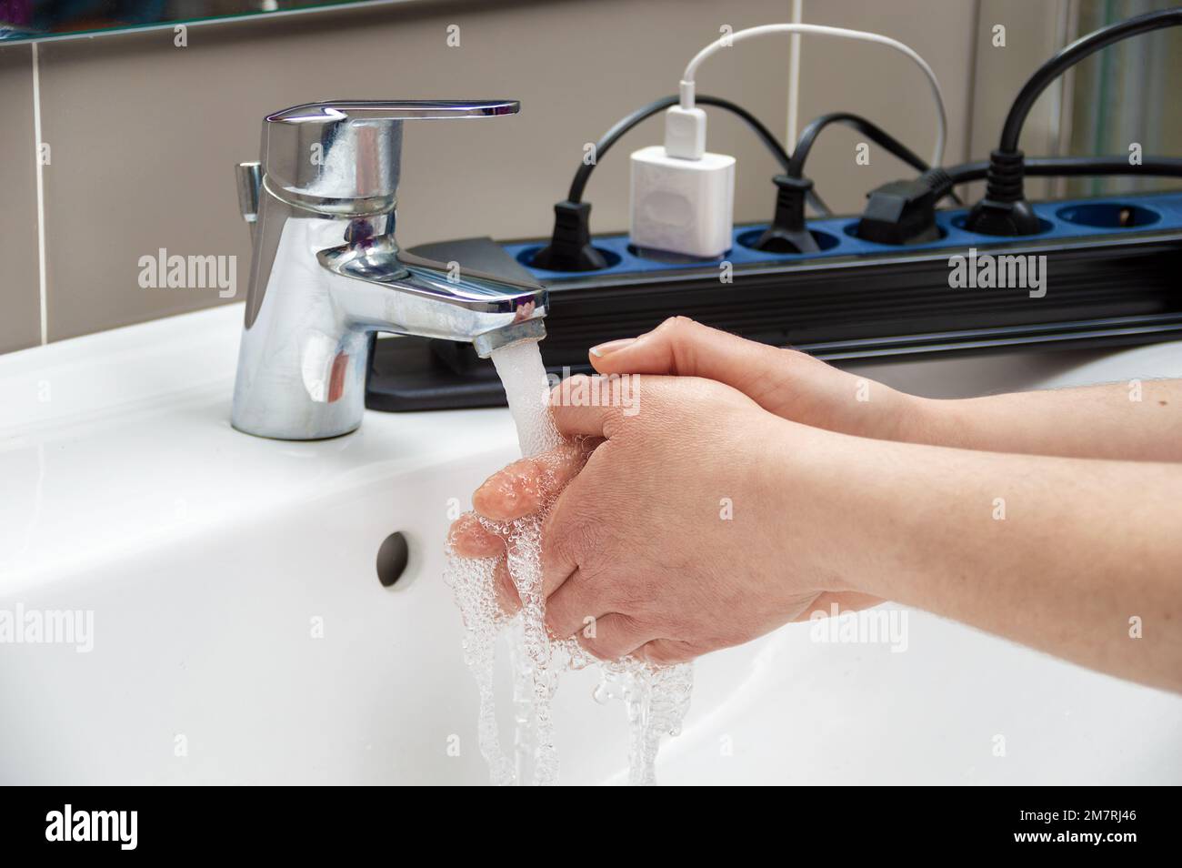 Close-up of an unrecognizable woman washing her hands with plug in an ...