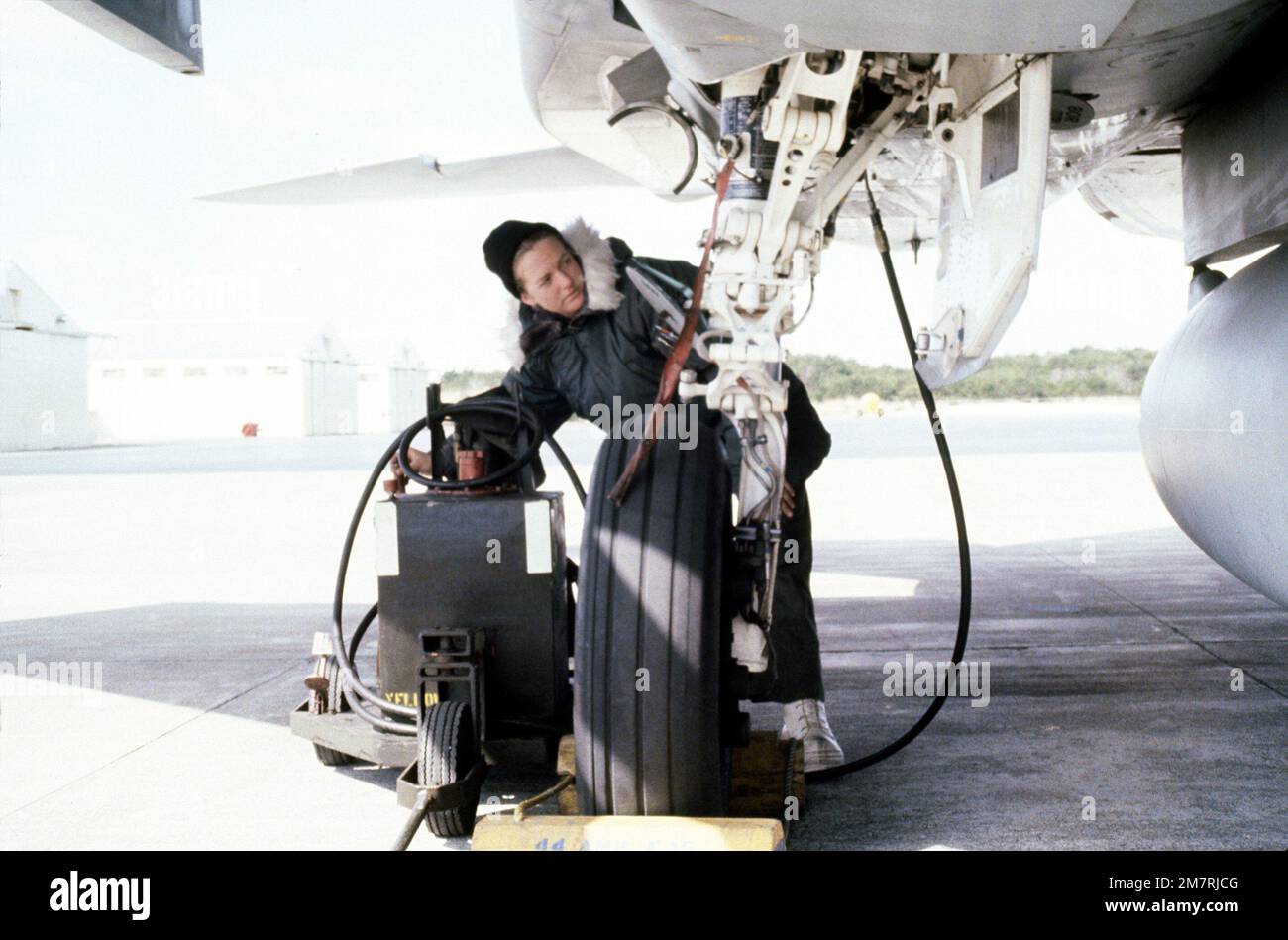 A ground crew member performs maintenance on an F-15 Eagle aircraft ...