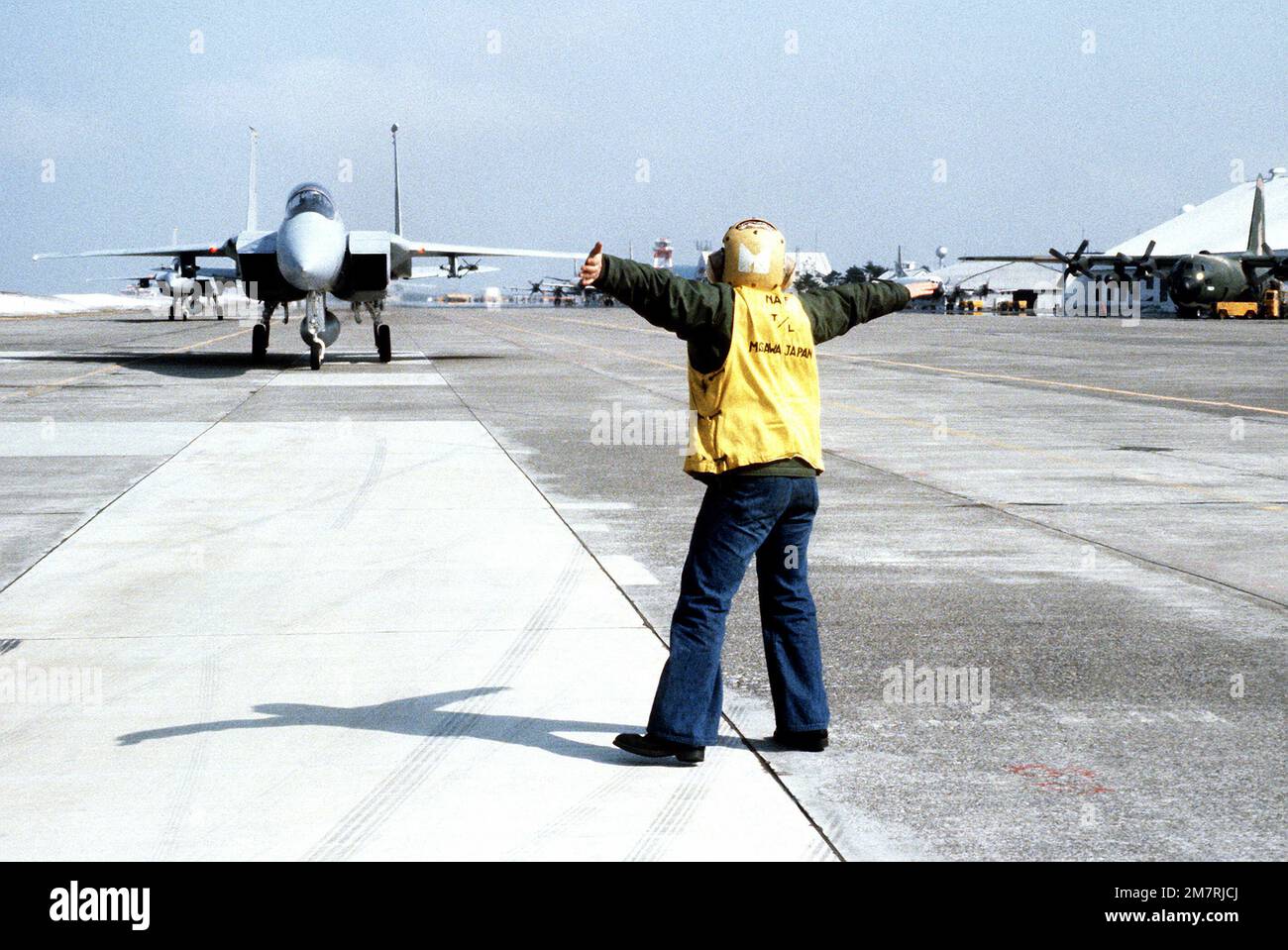 A ground crew member marshals F-15 Eagle aircraft into parking ...